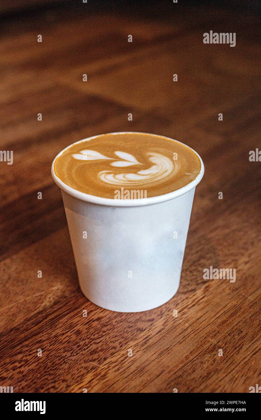 Close up of one takeaway cup with heart shape latte art on wood tabel ...