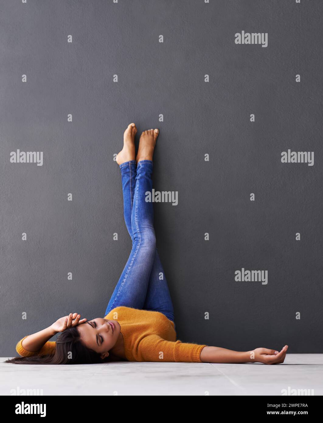 Woman, style and wall background for laying, feet and relaxing on floor ...