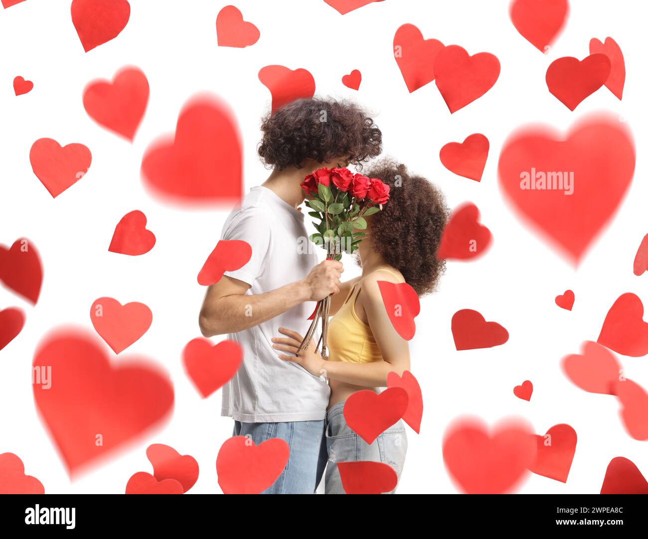 Full length shot of young couple kissing and hiding behind a bunch of ...