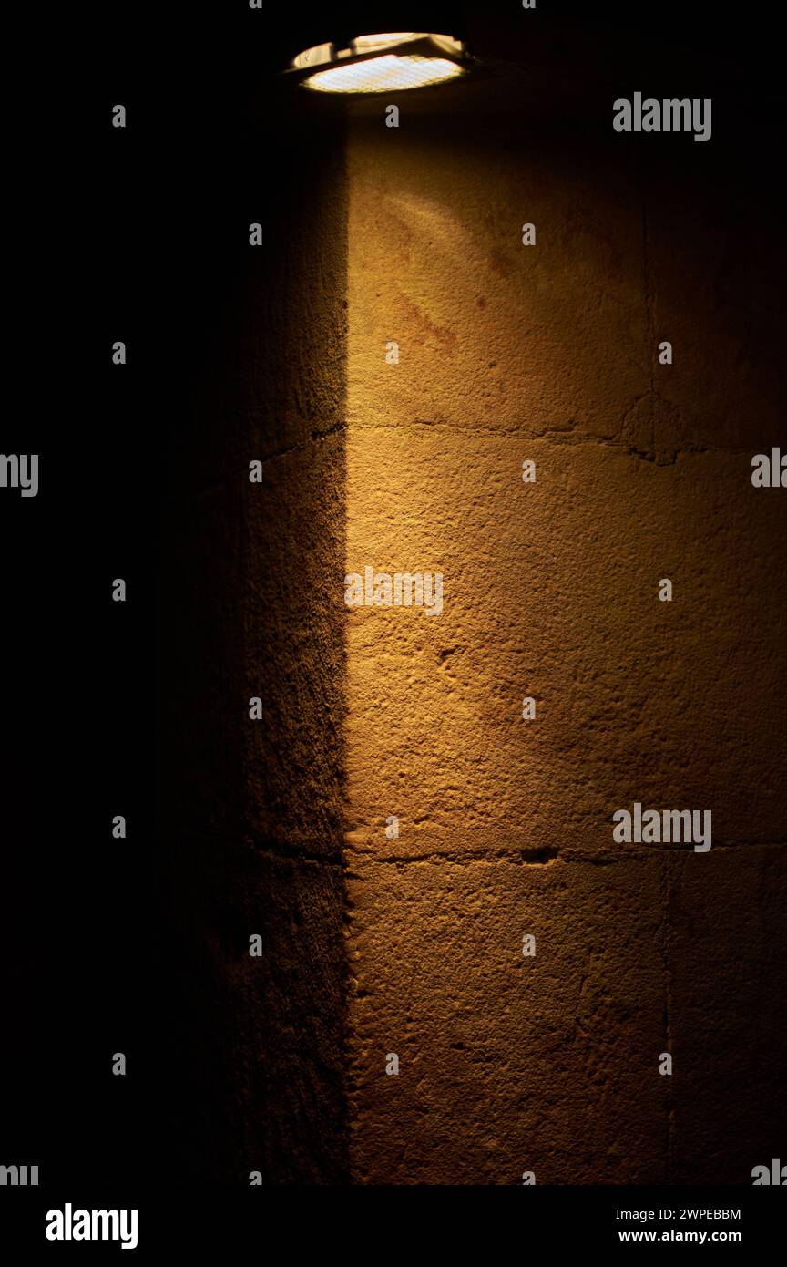 A bright light illuminates a dark wall, creating a dramatic contrast ...