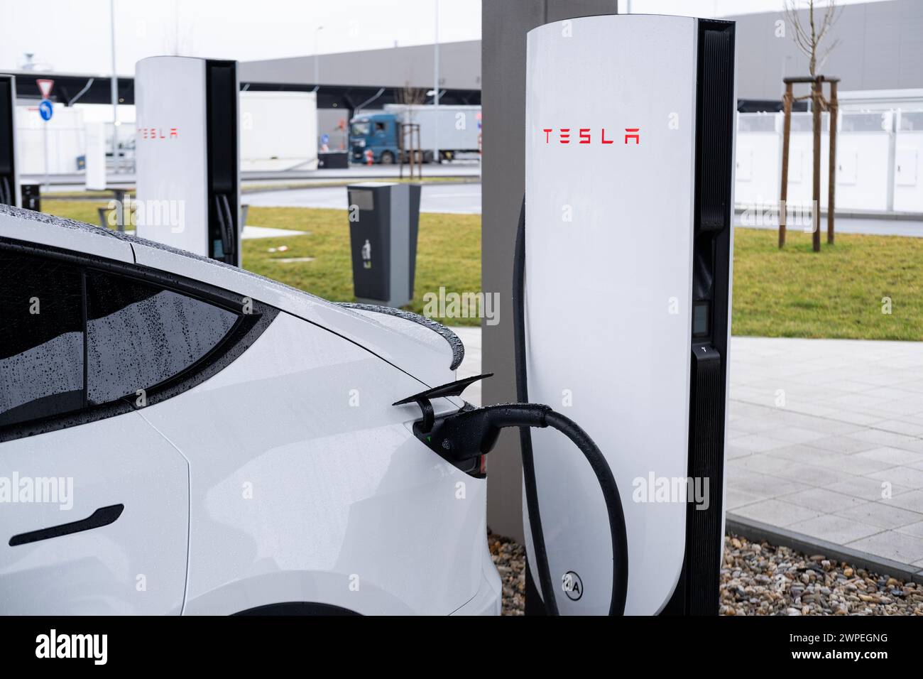 white Tesla electric car replenishes battery at charging station ...