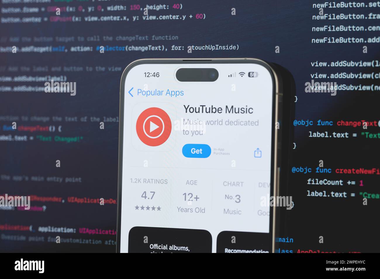 New York, USA - February 23, 2024: Youtube music on iphone screen in blurred code programming ...