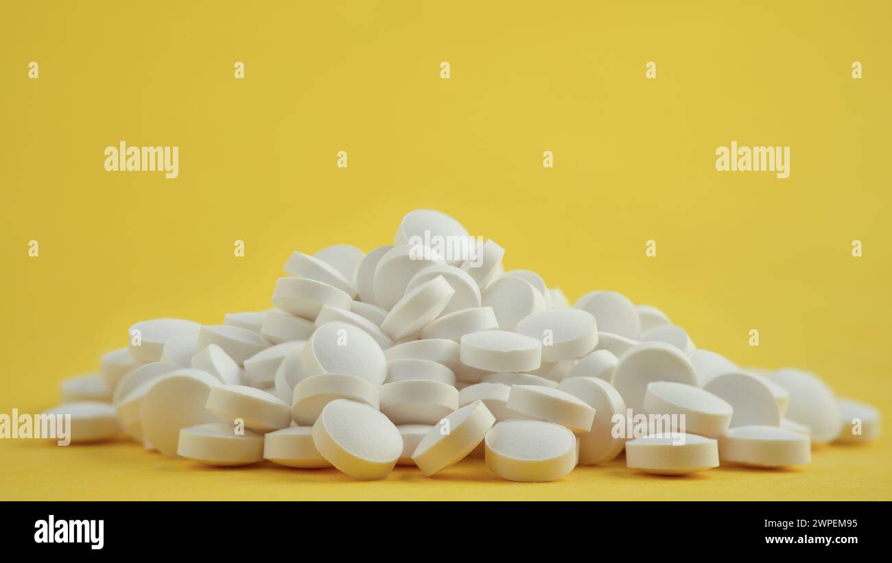 Close up photograph of a pile of white round shaped vitamin tablets on ...