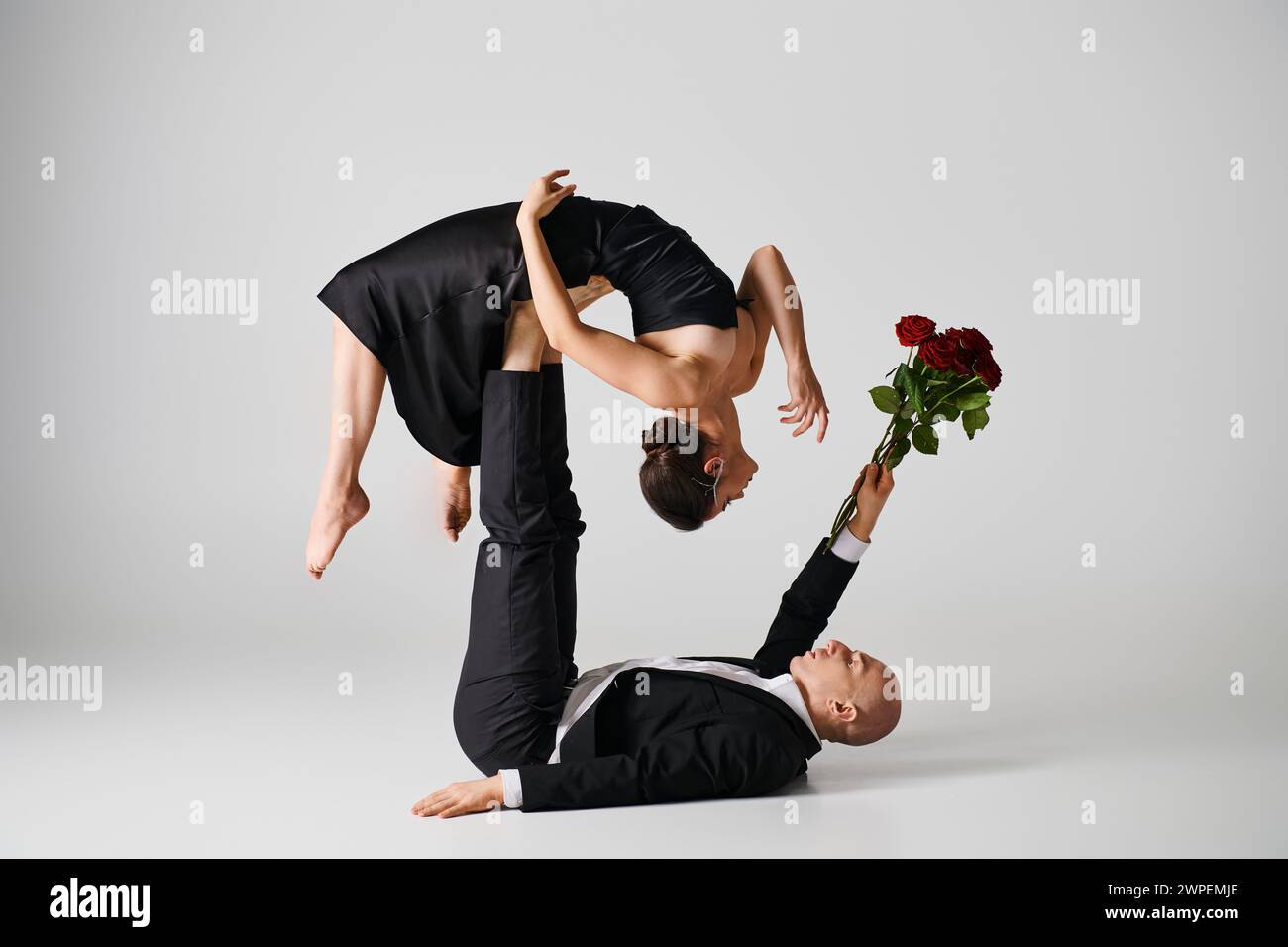 flexible woman in black attire balancing on feet of dancing partner ...