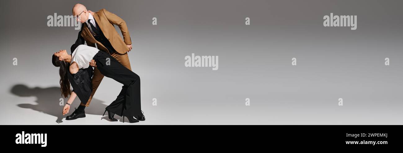 brunette woman in formal wear bending with support of man in glasses on ...