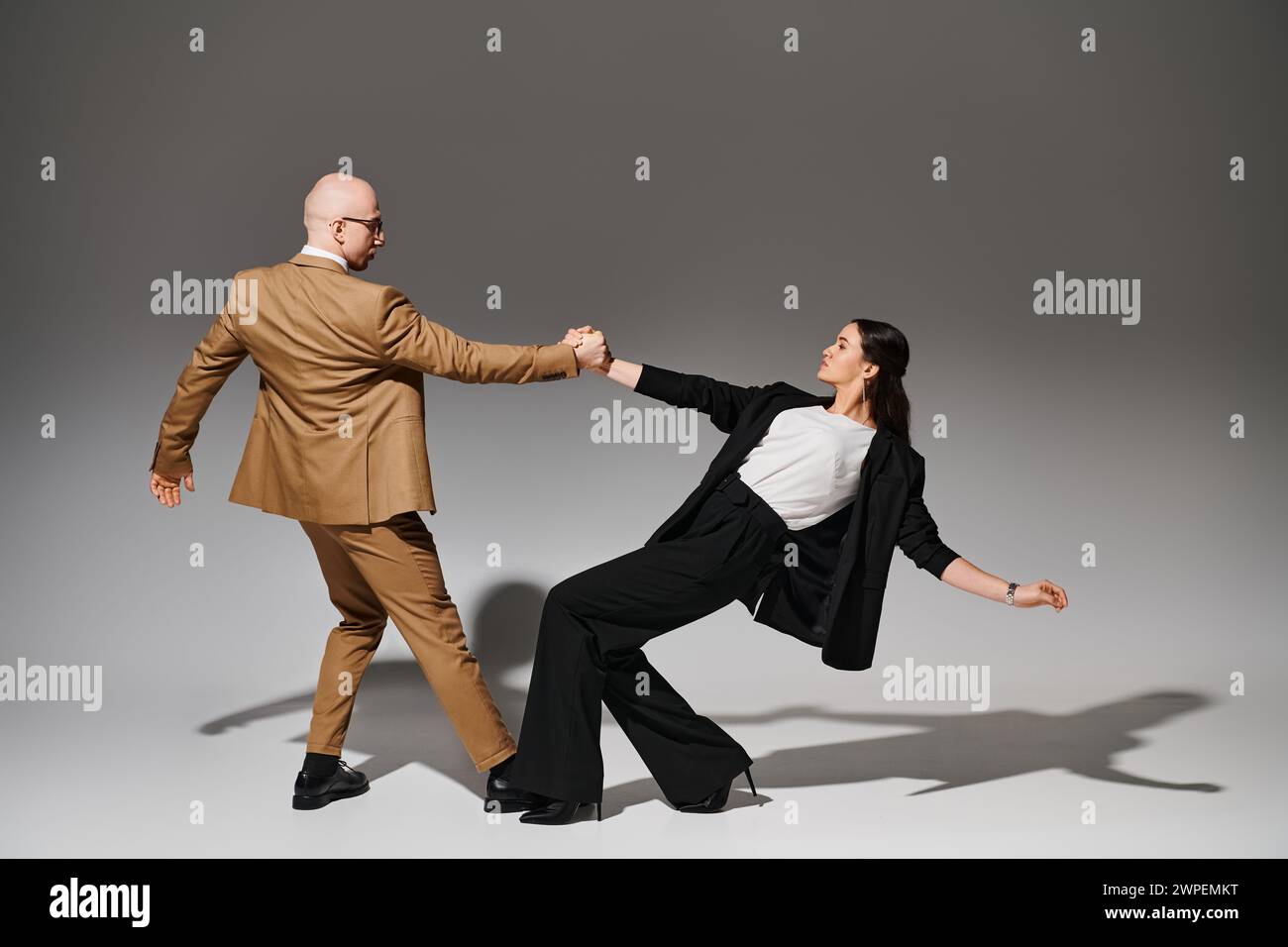 dance partners in suits holding hands during performance in studio with ...