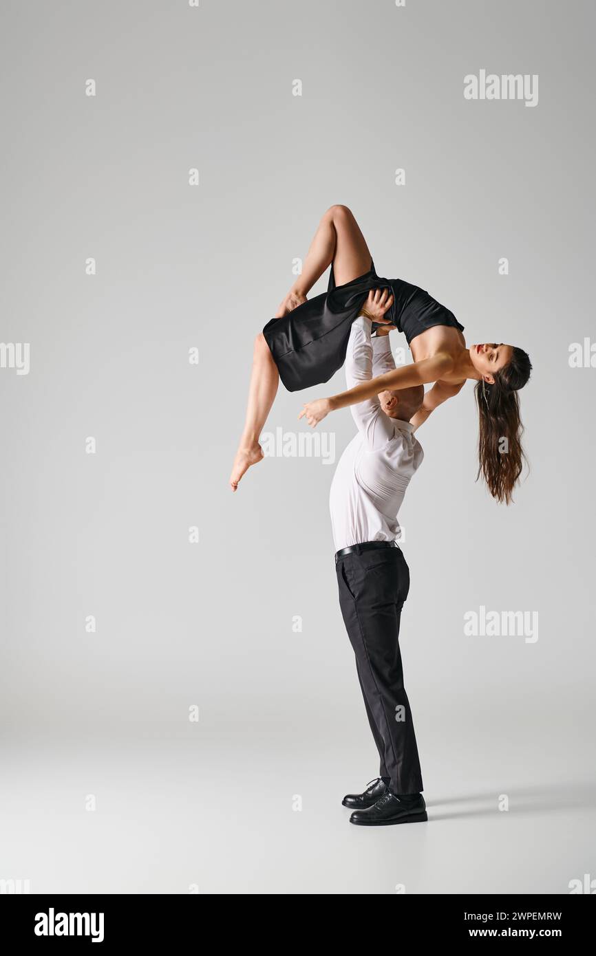dancer in suit lifting body of woman in black dress during performance ...