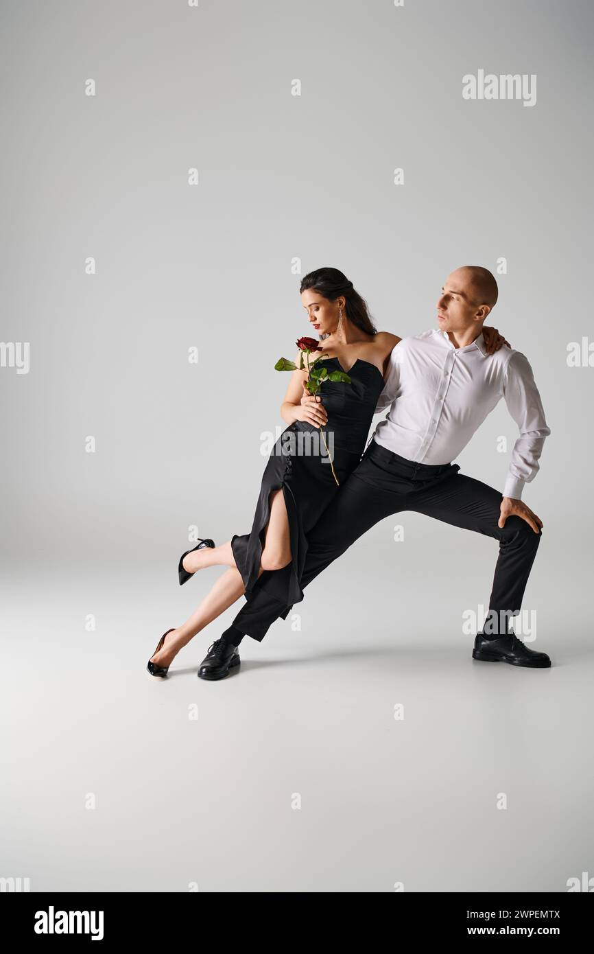 Elegant dance motion of young brunette couple, woman holding red rose ...