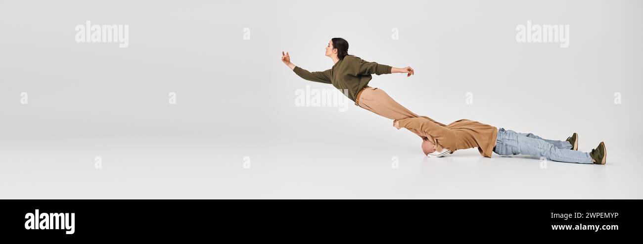 acrobatic woman in casual wear balancing in air with support of her ...