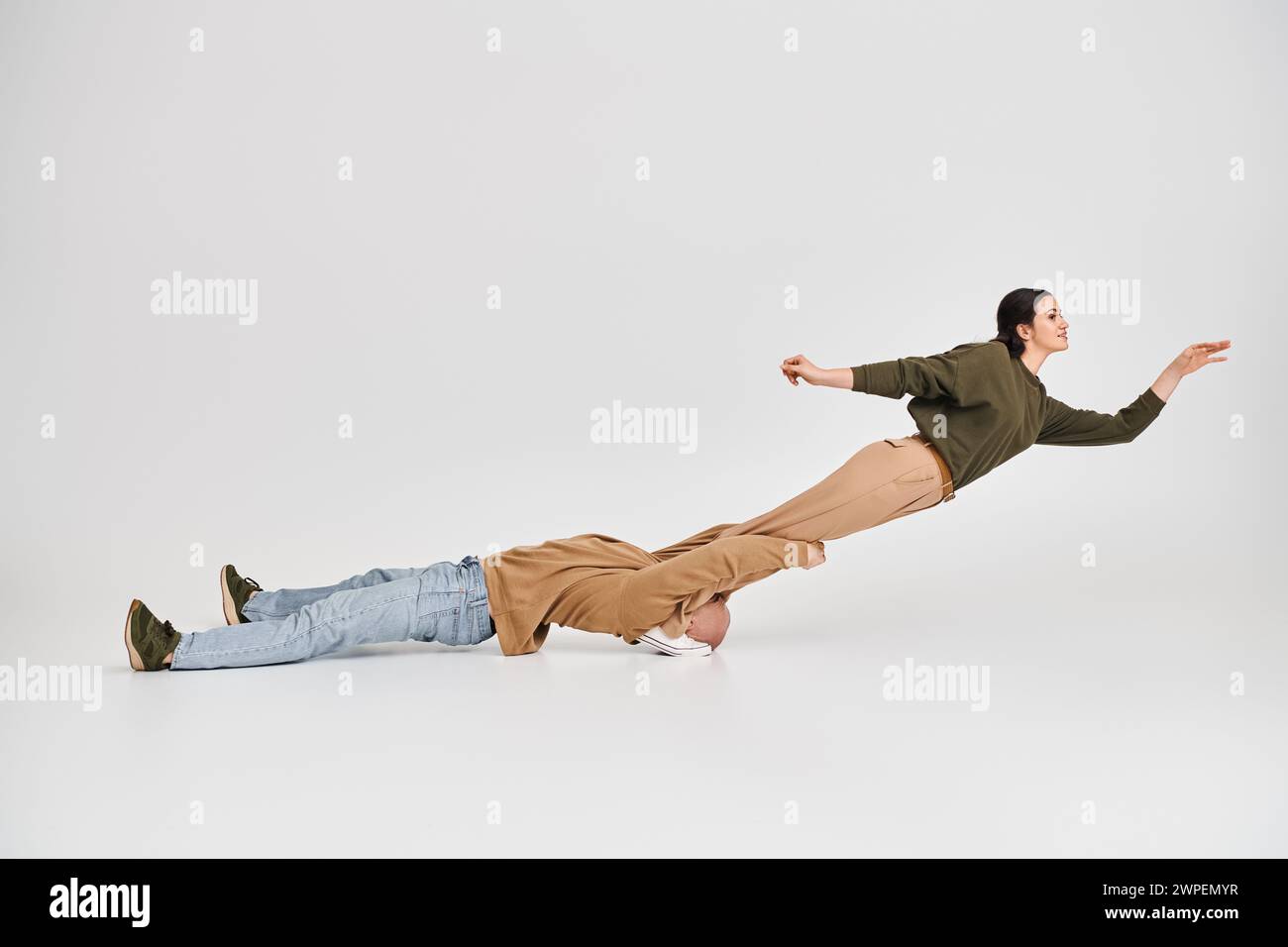 acrobatic woman in casual wear balancing in air with support of her ...