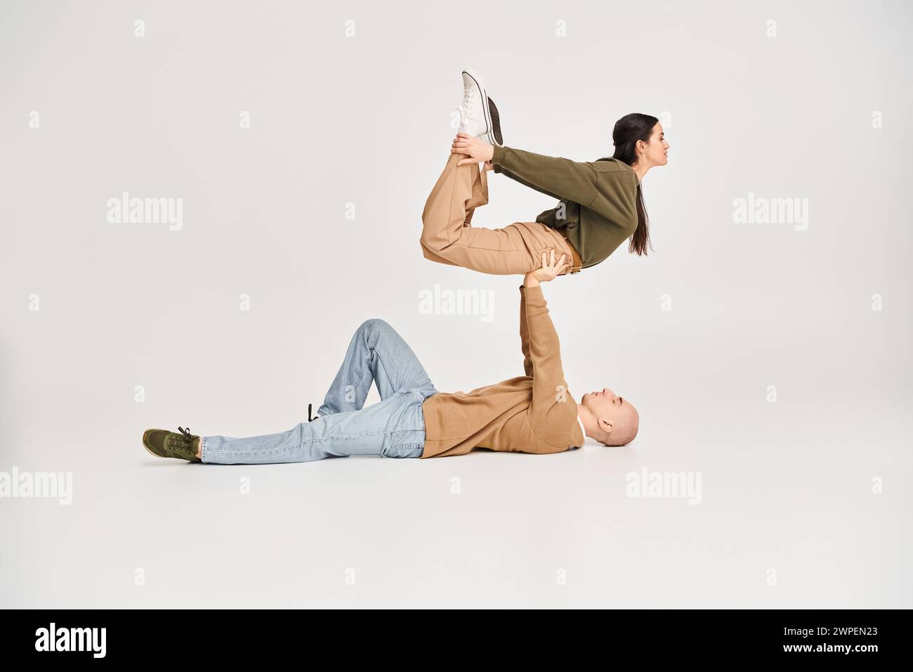 strong man in casual wear lying on floor and lifting brunette woman on ...
