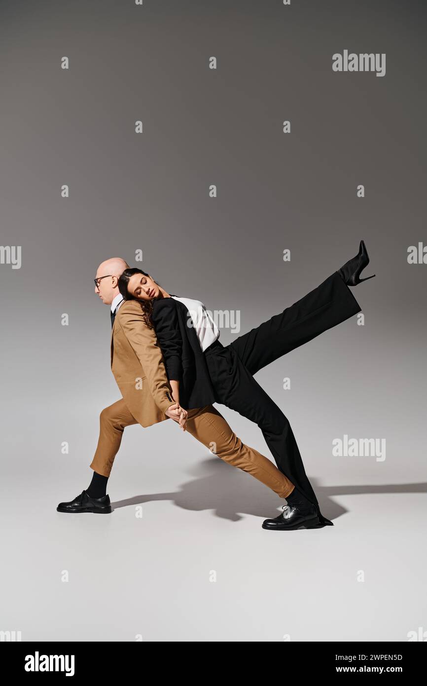 partners in coordinated dance move, woman in suit leaning on back of ...