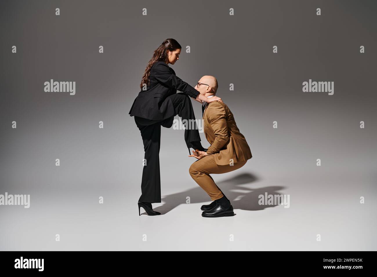 brunette woman balancing in her high heels while stepping on hand of ...