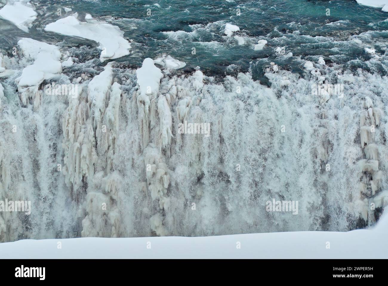 Majestic frozen waterfall with icicles and snow viewed from the side of ...