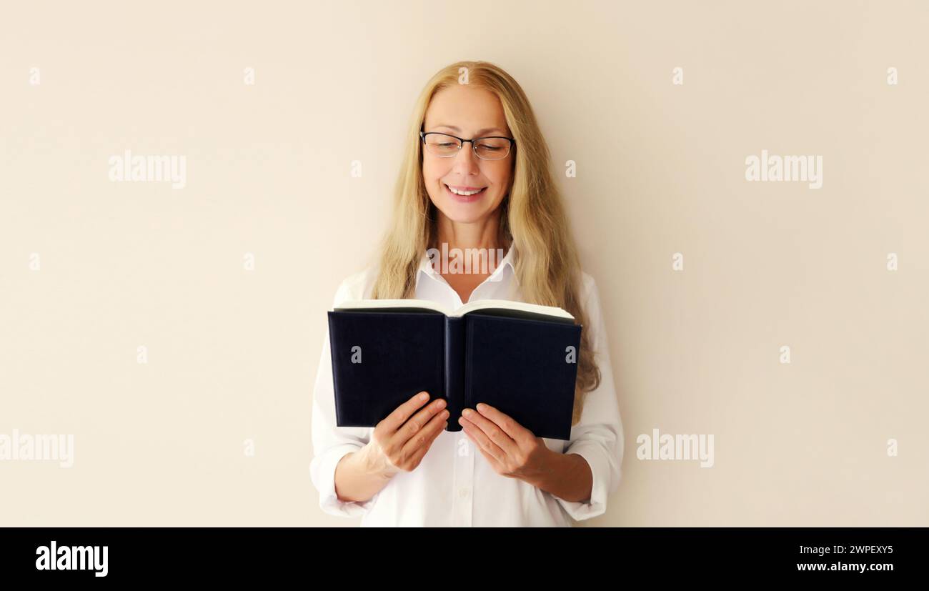 Portrait of happy caucasian middle-aged woman reading book with blank ...