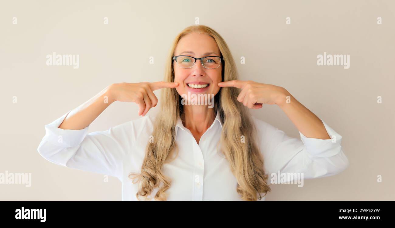 Portrait of happy smiling middle-aged woman points with fingers to her ...