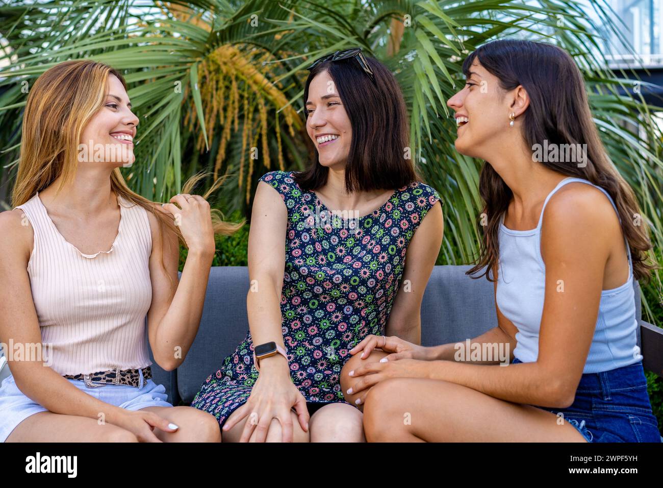 Three beautiful young women chatting on a couch Stock Photo - Alamy