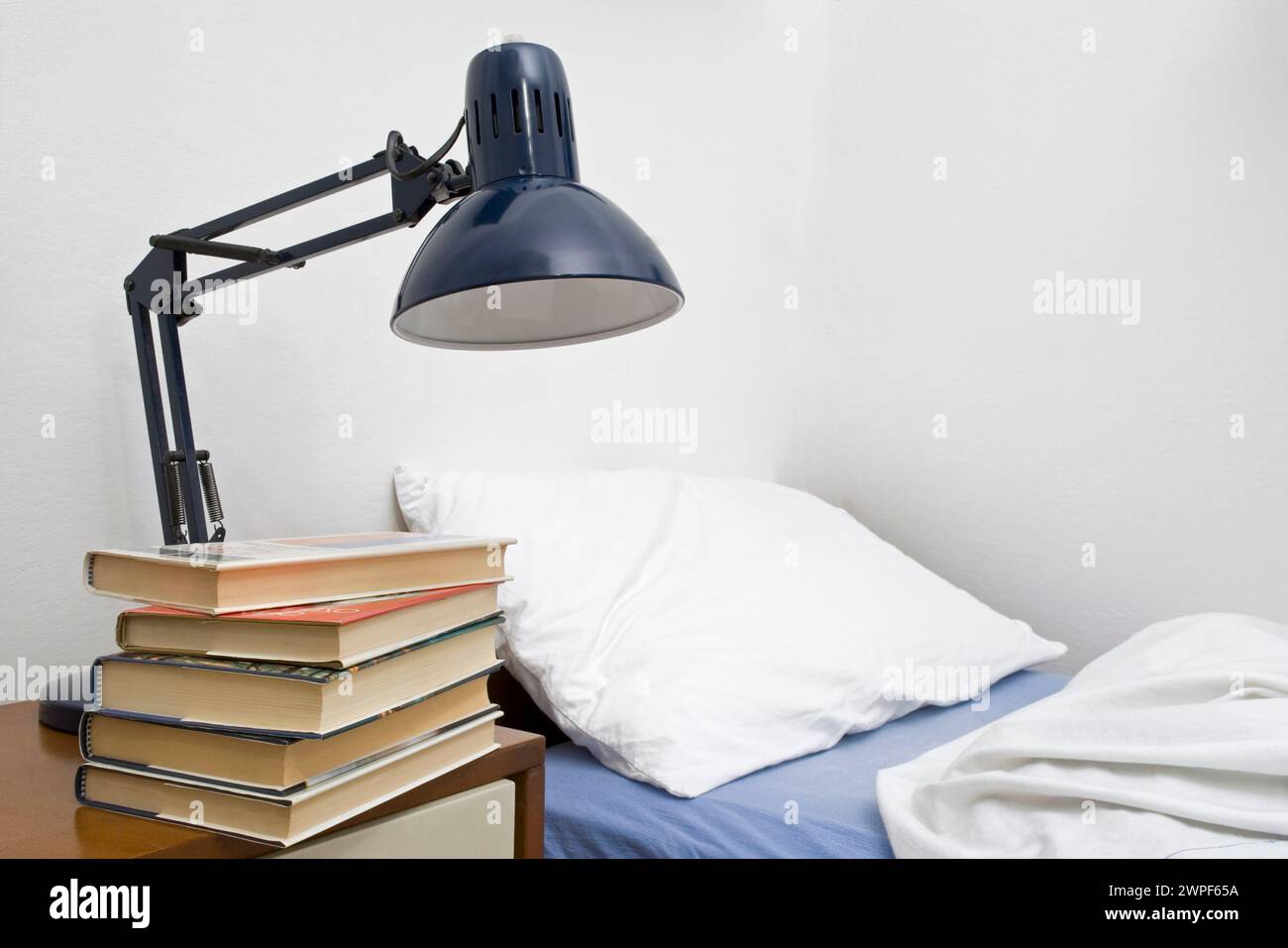 bedside lamp and piled books in bedroom Stock Photo - Alamy