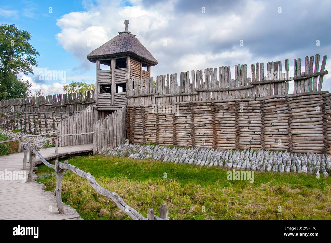 A wooden fence with a guard tower and a gate leading to the interior of ...