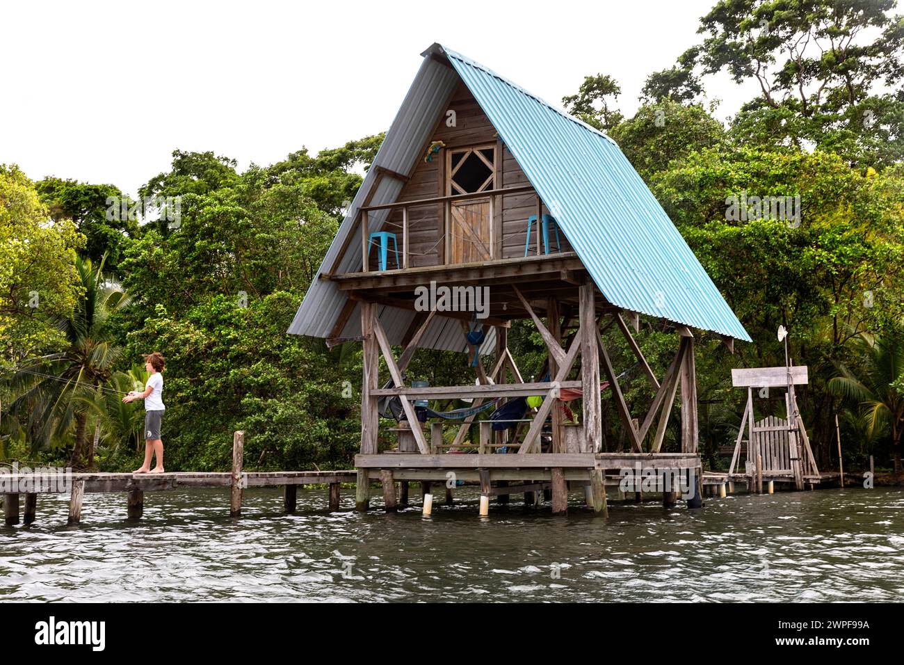 Kid tourist standing on a wooden pier and fishing, Overwater Bungalow ...