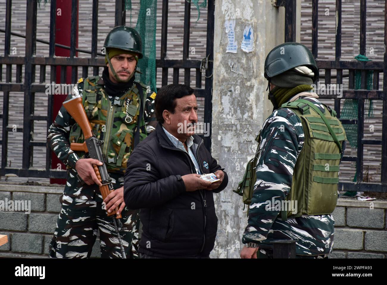 A paramilitary trooper checks the identity card of a man outside a ...