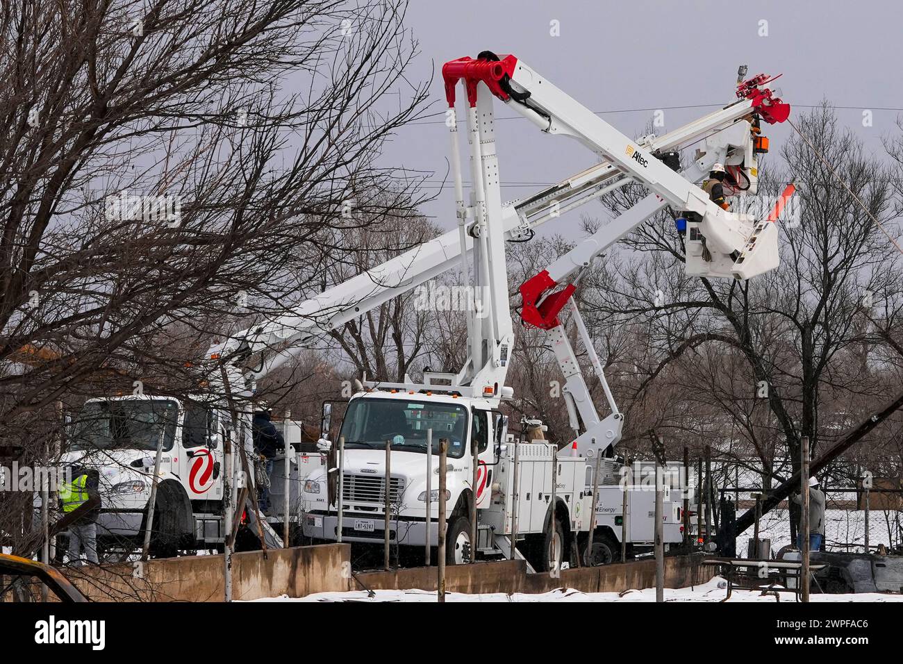 Utility workers from Xcel Energy labor on power lines near a home ...