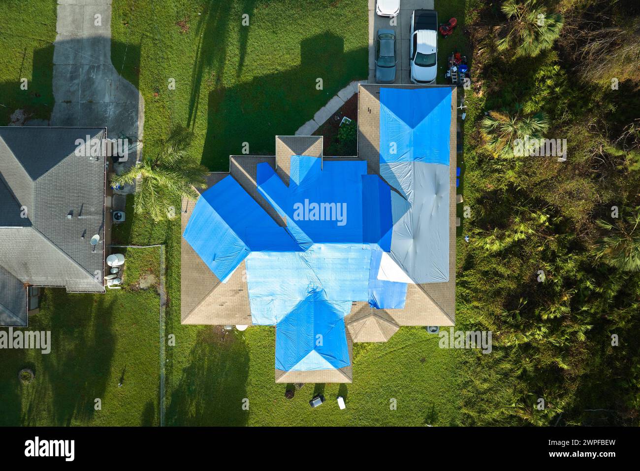 Aerial view of damaged in hurricane Ian house roof covered with blue ...