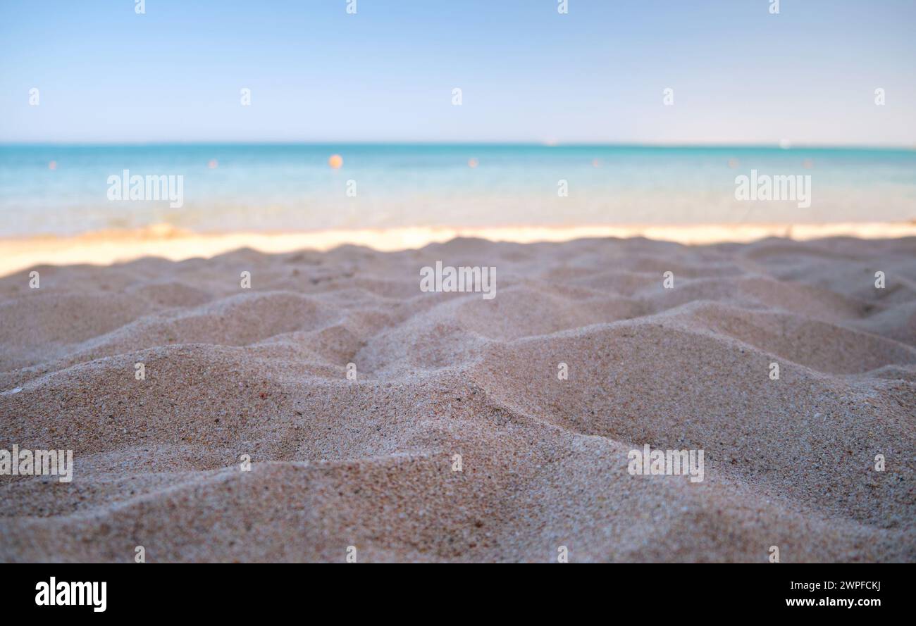 Close up of clean yellow sand surface covering seaside beach with blue ...
