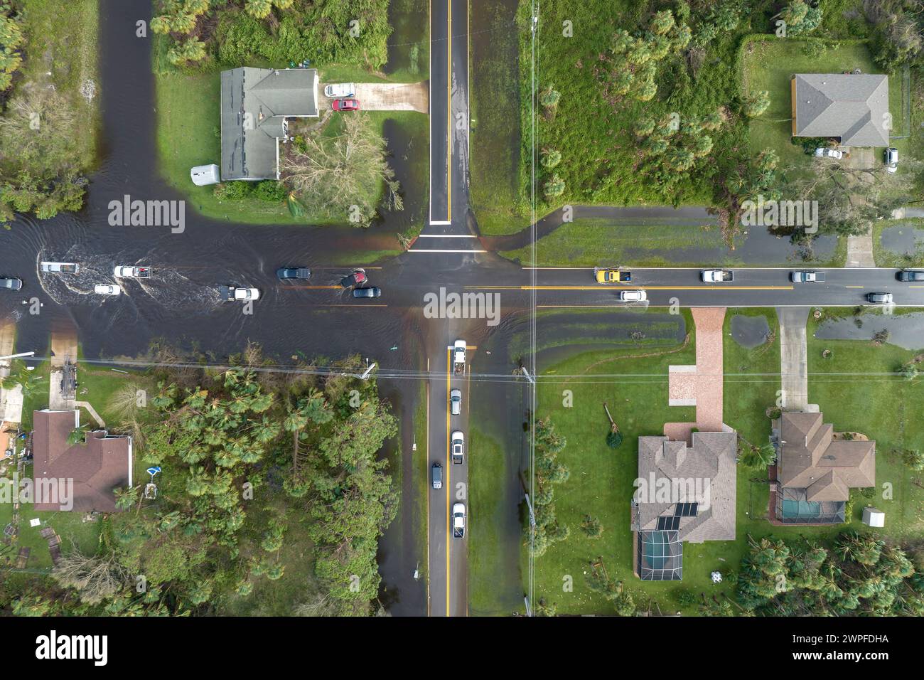 Hurricane flooded street with moving cars and surrounded with water ...
