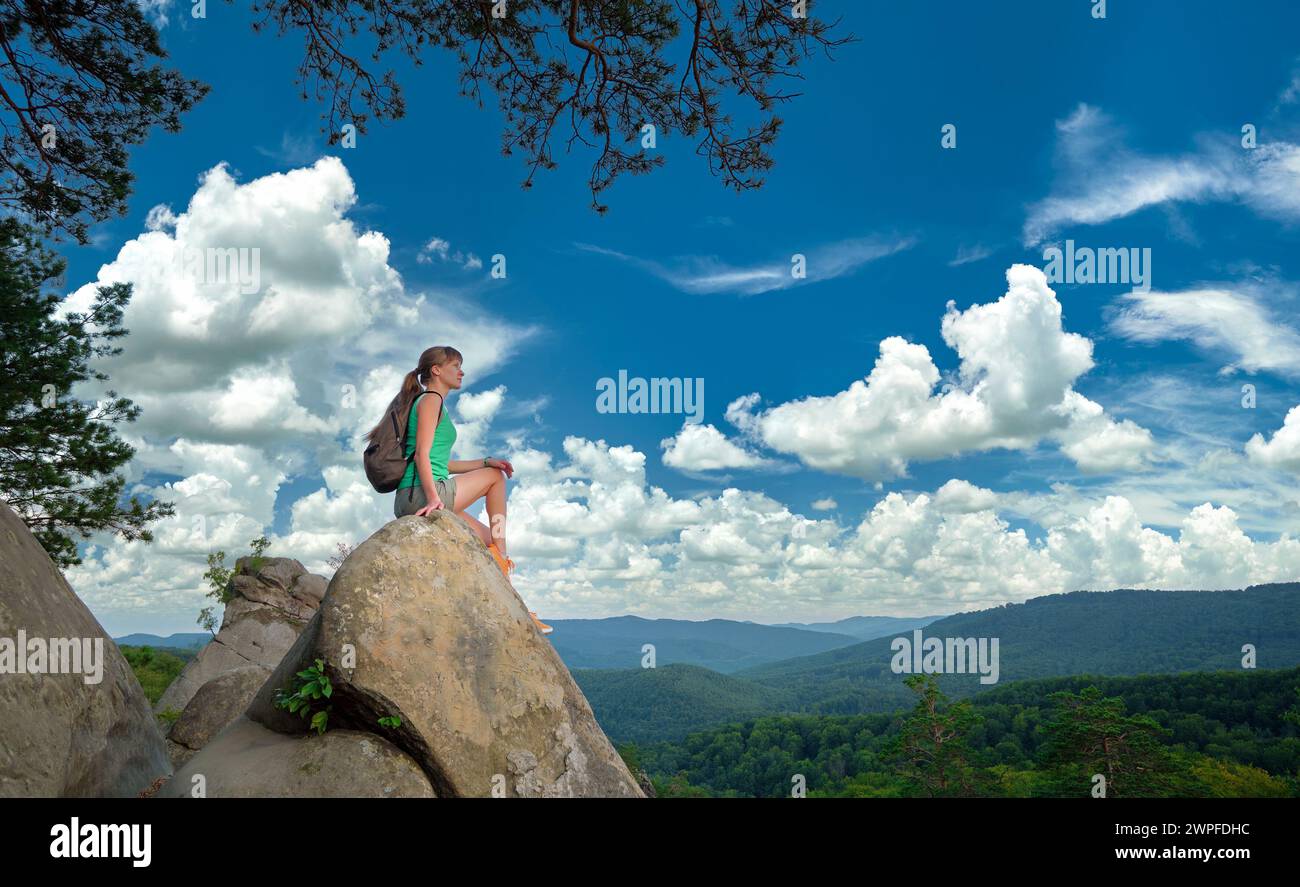 Hiker woman resting on rocky mountain top enjoying summer nature during ...