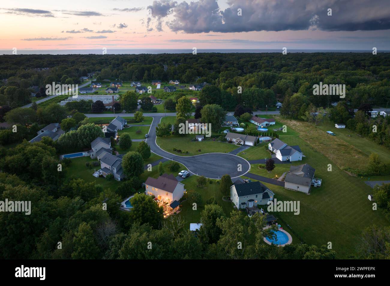 Residential illuminated homes at sunset in suburban sprawl development ...