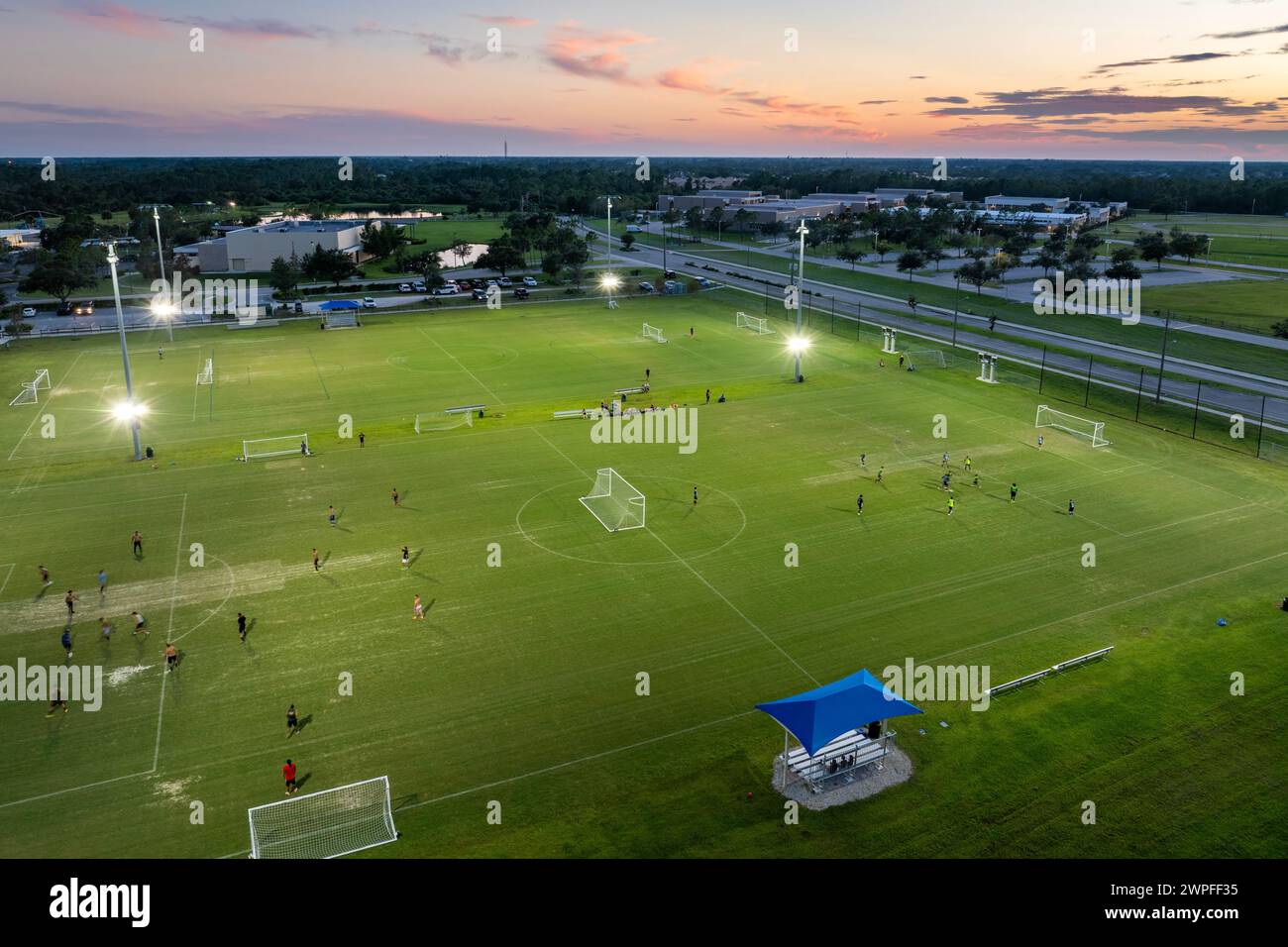 Sportsmen playing football game on illuminated stadium in public sports ...