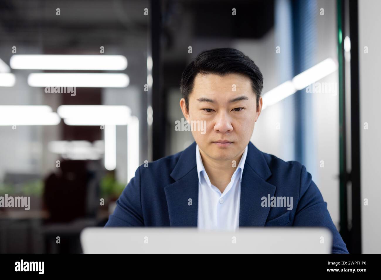 Serious businessman working diligently at his laptop in a modern office ...