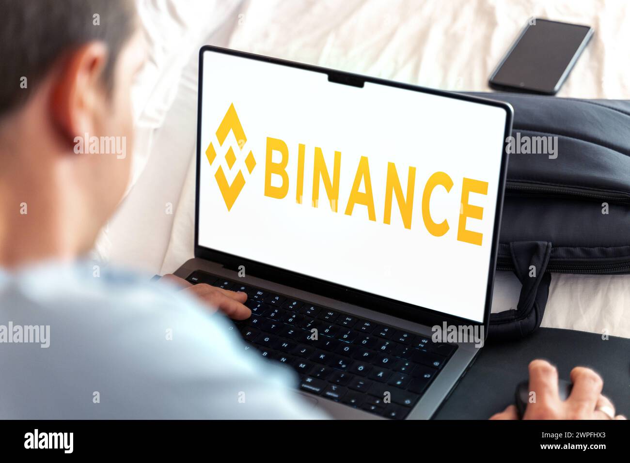 Germany - March 7, 2024: Man sitting at a laptop computer, the BÖRSE BINANCE logo can be seen on ...