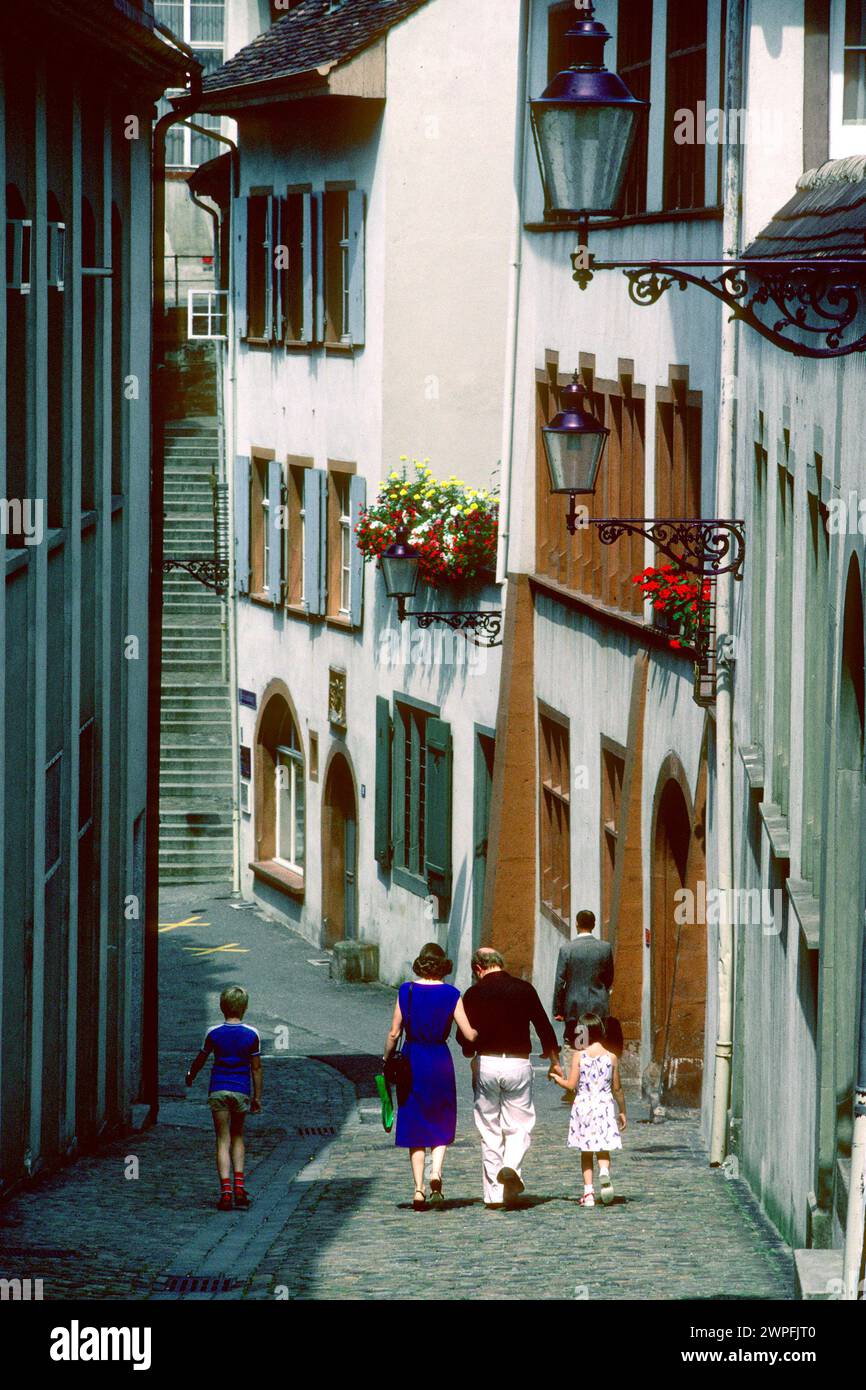 Family walking down a street in the old part of the city in 1980, Basel ...