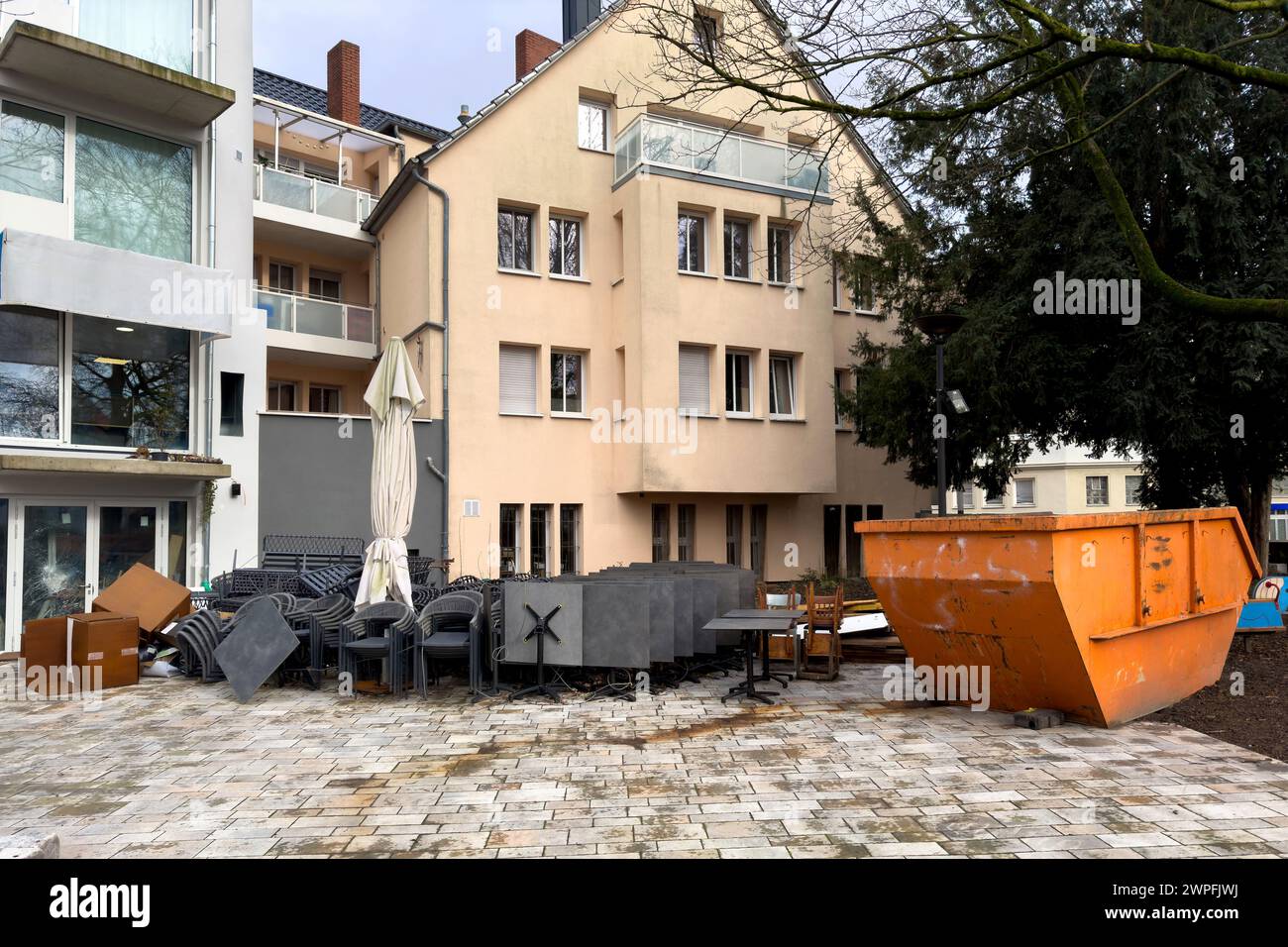 Plastic tables and chairs from a street cafe are stacked outside a ...