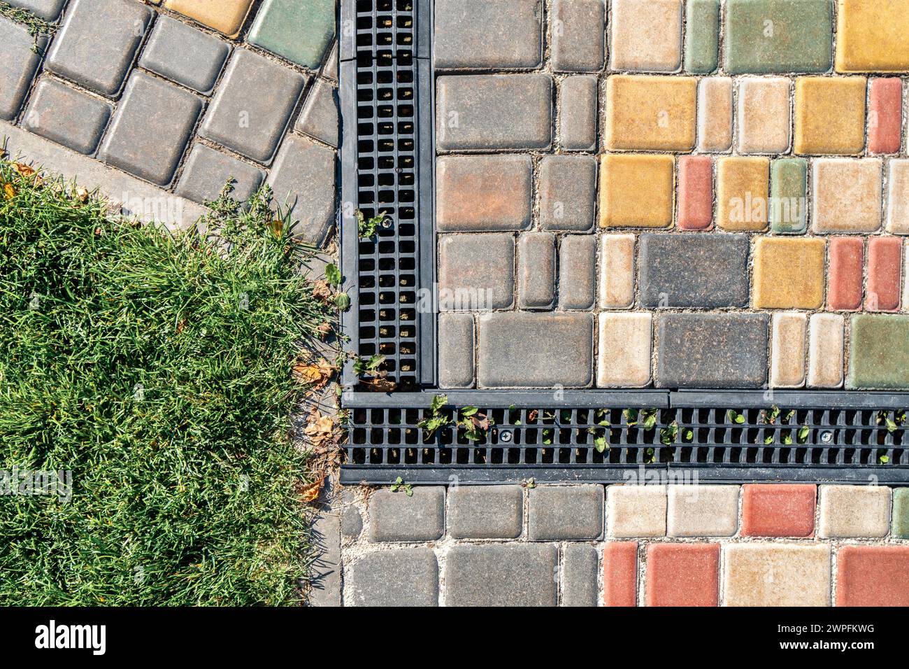 Paved road with color stones and storm drain on sunny day. Modern ...