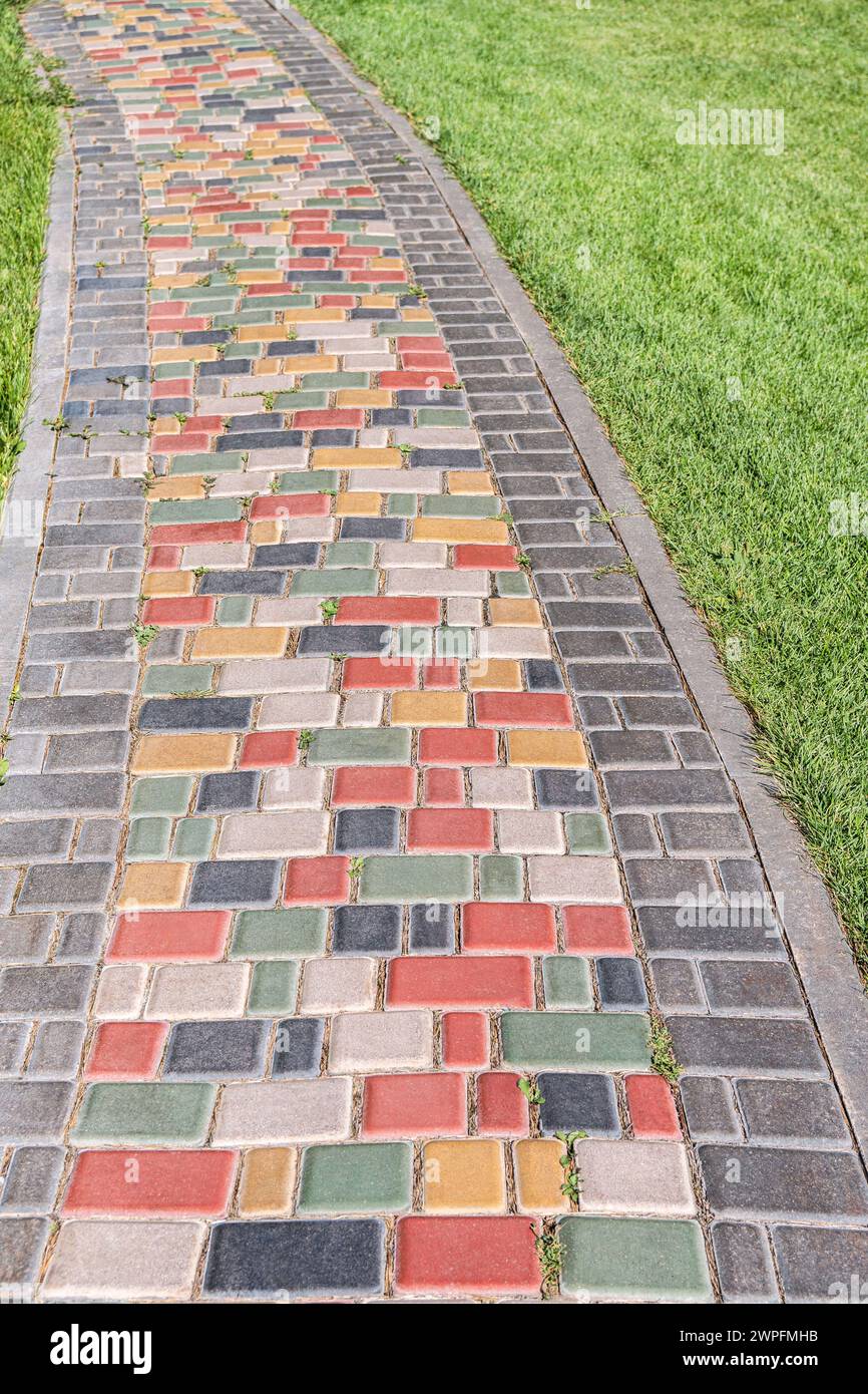 Colorful paved road across lush lawn on sunny day. Pathway with bright ...