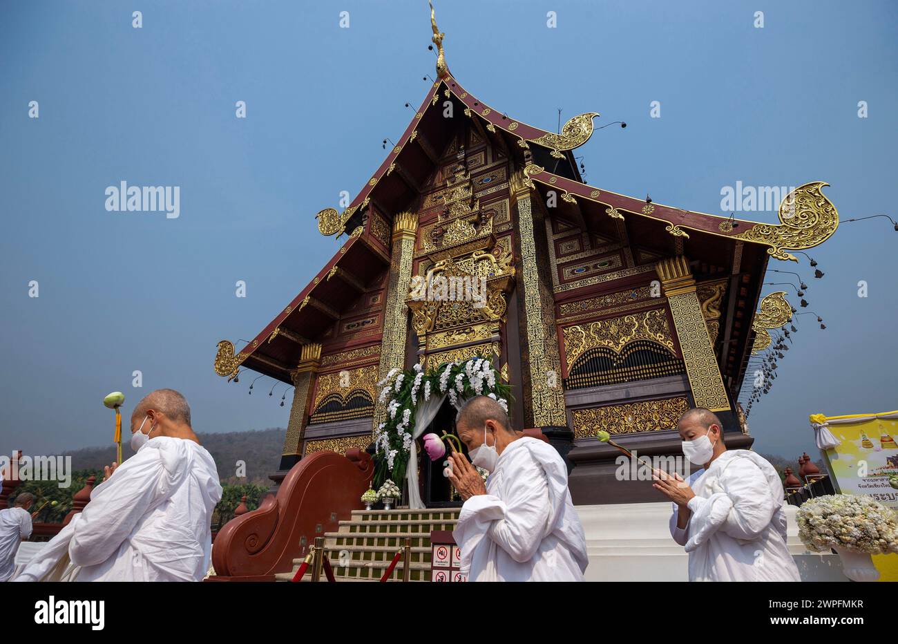 Thai Buddhist nuns hold candles and flowers as they pay obeisance to ...