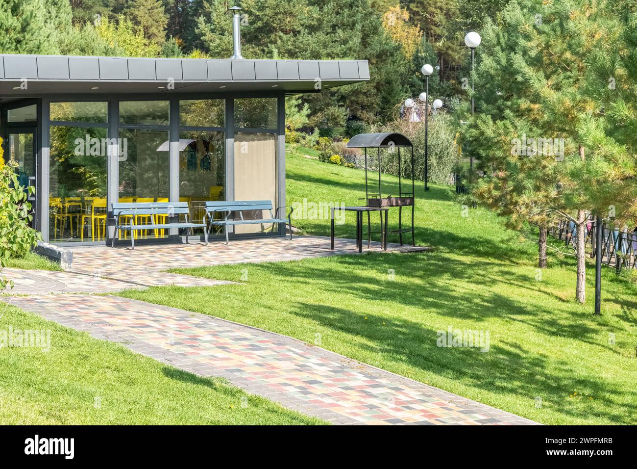 Guest house with glass walls and barbeque zone in yard at summer resort ...