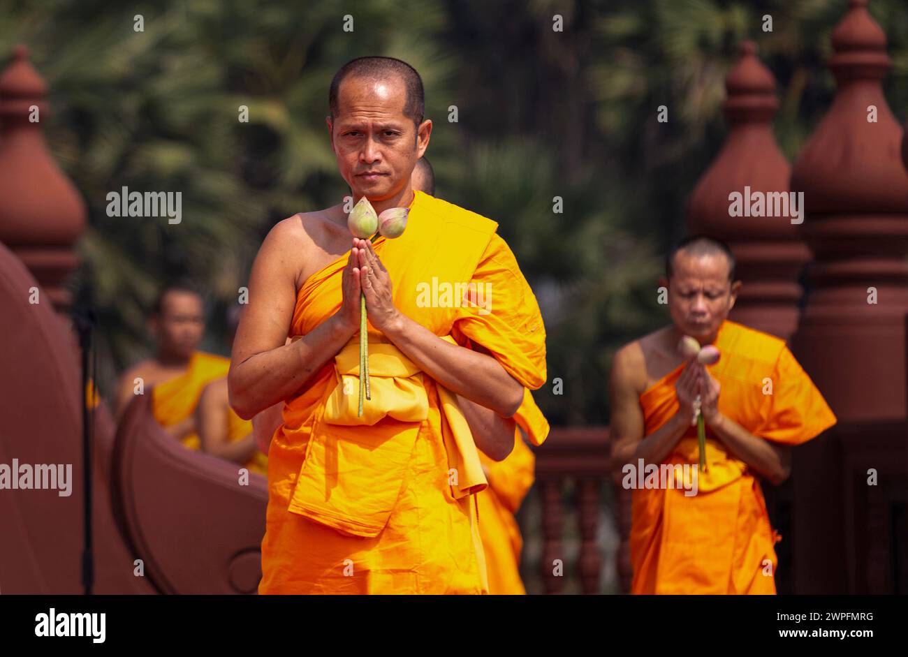 Thai Buddhist monks hold flowers as they pay obeisance to the sacred ...
