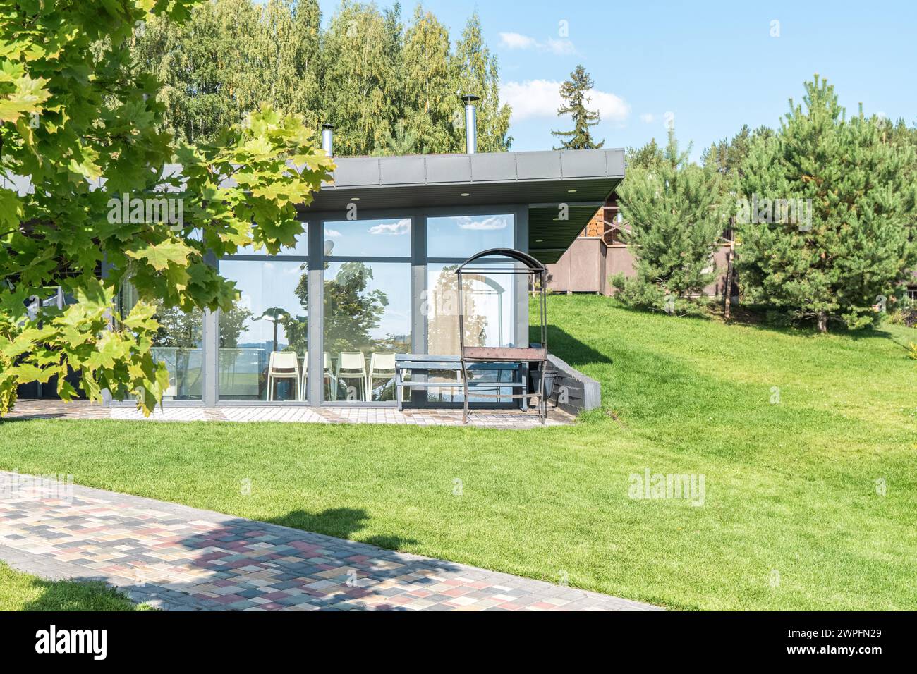 Guest house with glass walls and barbeque zone in yard at summer resort ...