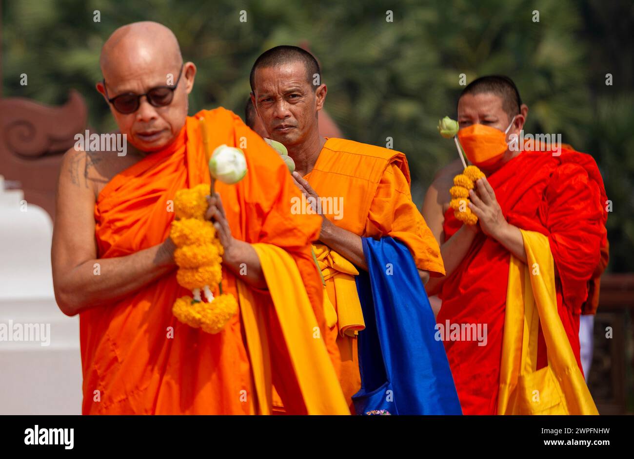 Thai Buddhist monks hold flowers as they pay obeisance to the sacred ...