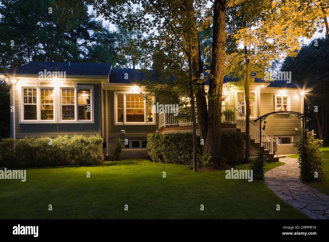 Tan wood plank cladded bungalow style home with landscaped backyard ...