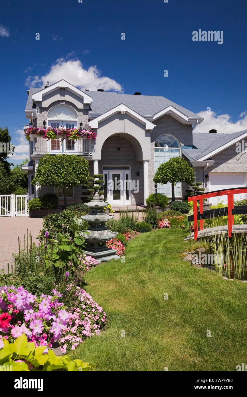 Grey brick with white trim two story home and red wooden footbridge ...