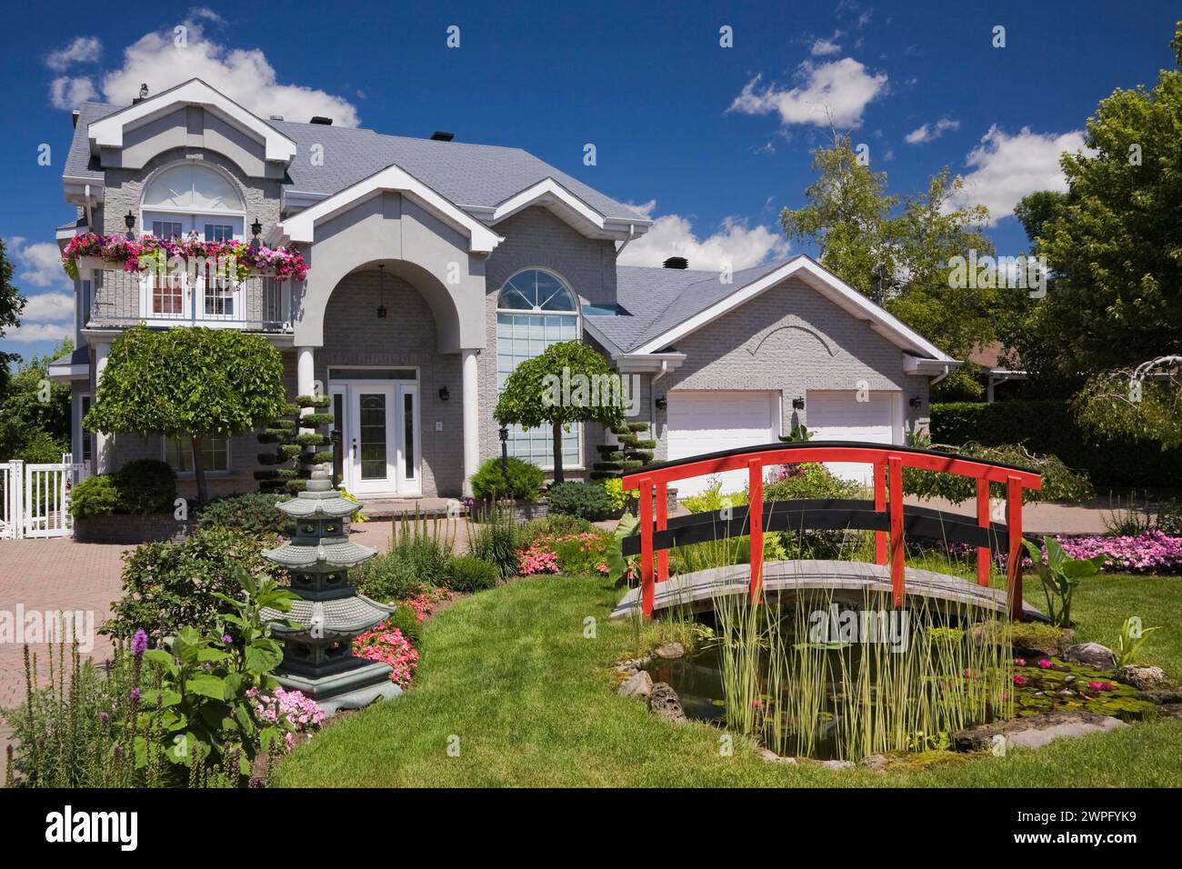 Grey brick with white trim two story home and red wooden footbridge ...