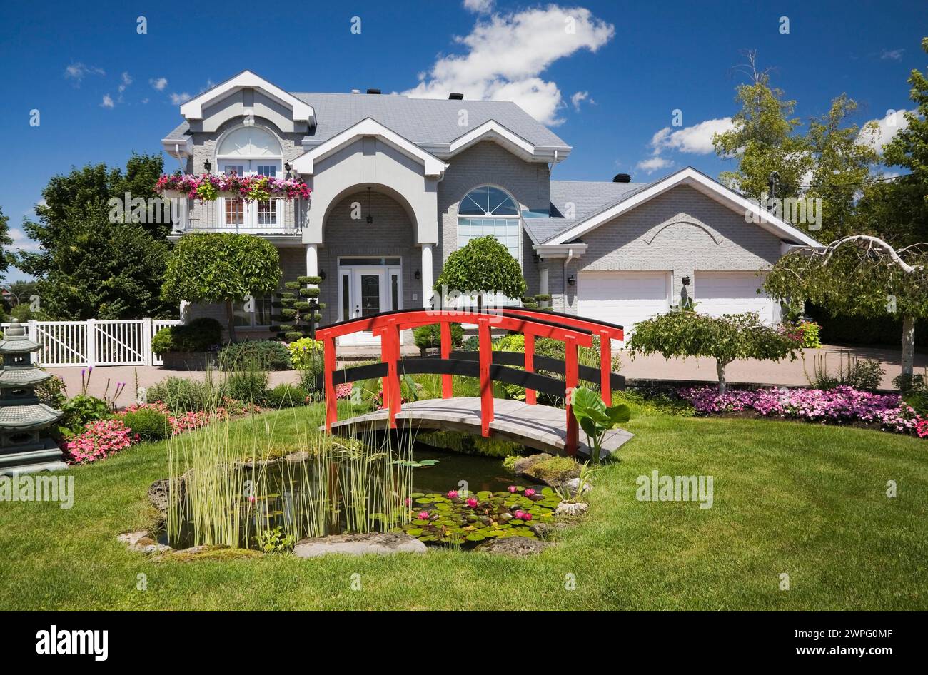 Grey brick with white trim two story home and red wooden footbridge ...