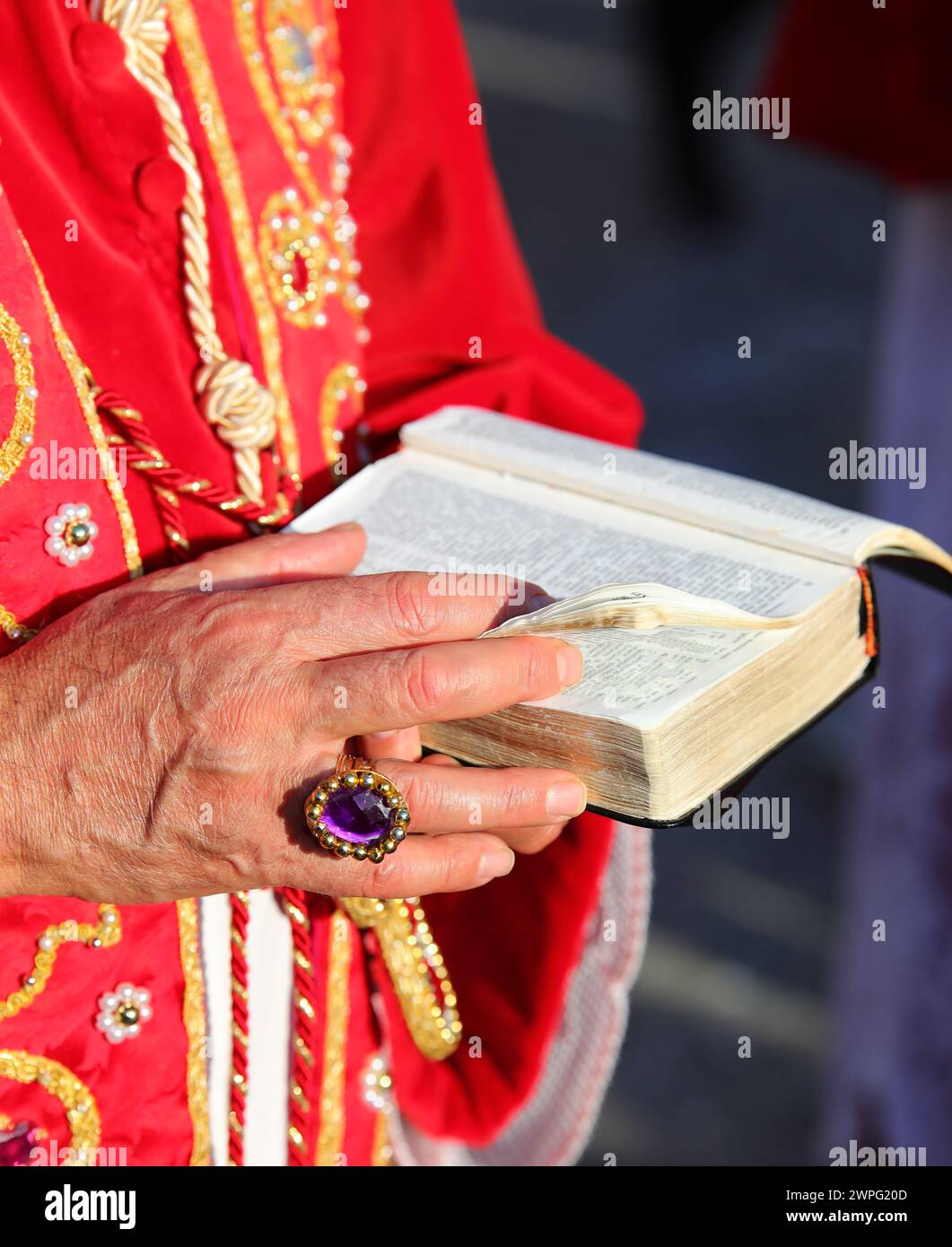 Hand of elderly priest wearing large ring holding Bible during ...