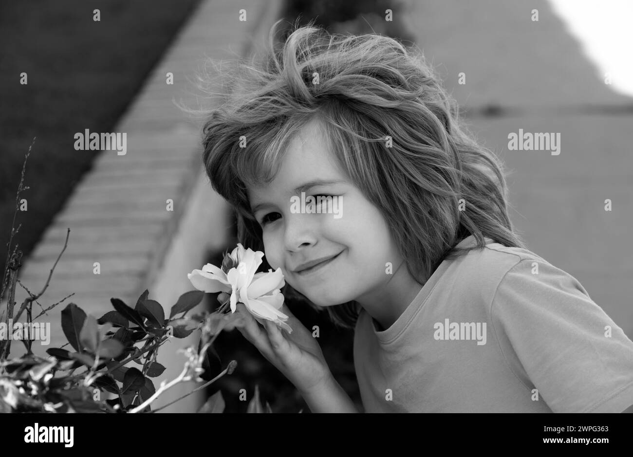 Beautiful blond little child with long hair smelling flower. Spring ...