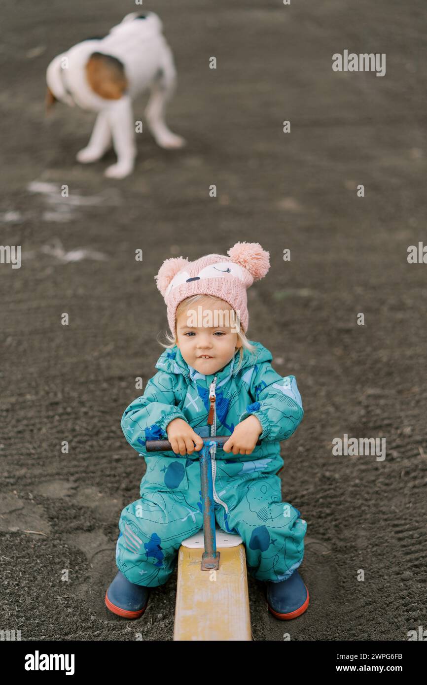 Little girl swinging on a swing-balancer biting her lip Stock Photo - Alamy